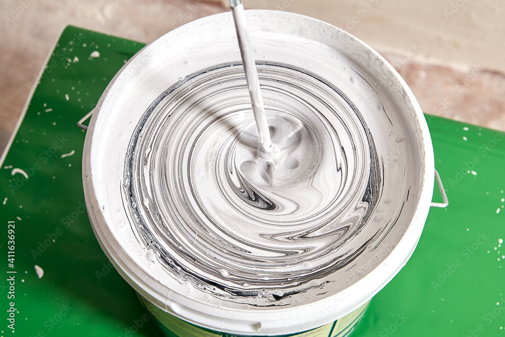 House painter mixes two paints using mixer for bucket with paddle ...