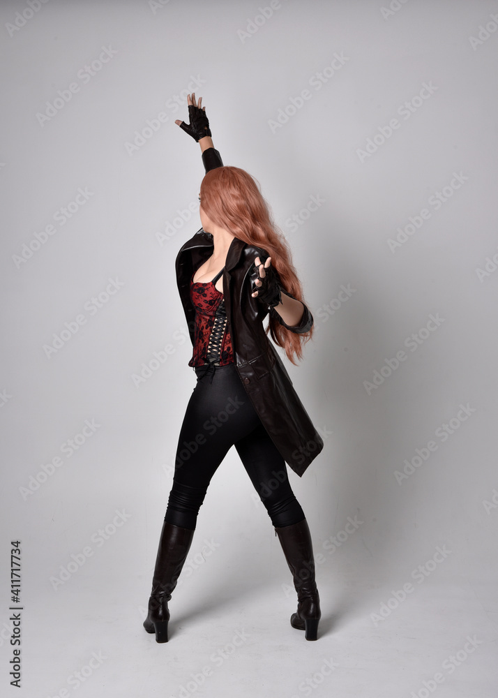 full length portrait of girl with long red hair wearing dark leather ...