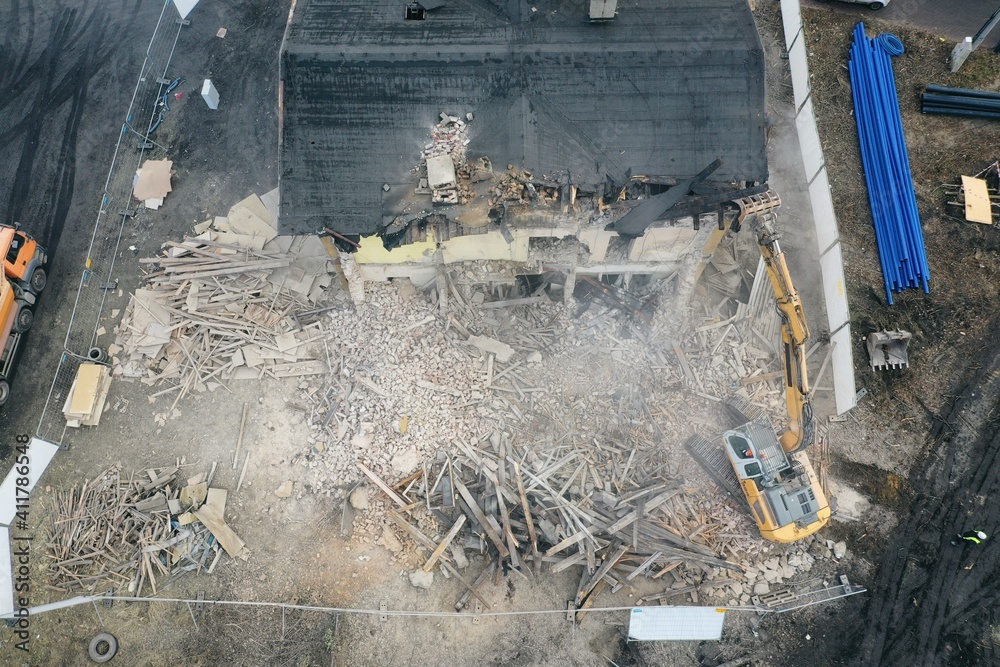 Yellow excavator destroys building. Heavy duty machine is demolishing a ...