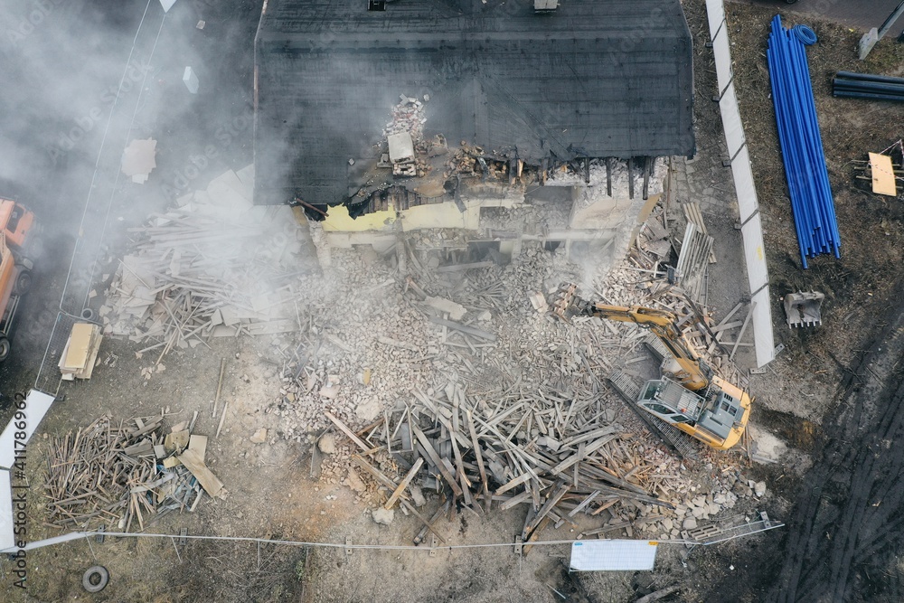 Yellow excavator destroys building. Heavy duty machine is demolishing a ...
