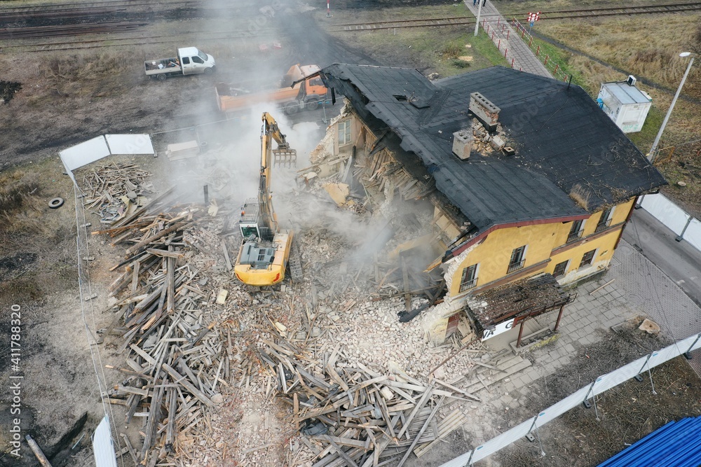 Yellow excavator destroys building. Heavy duty machine is demolishing a ...