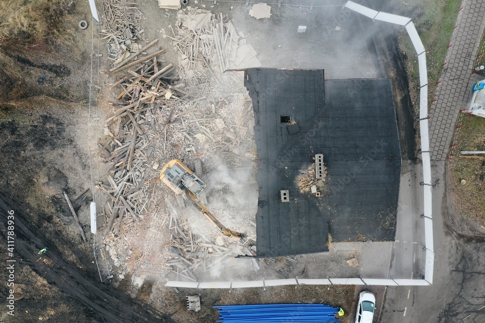 Yellow excavator destroys building. Heavy duty machine is demolishing a ...