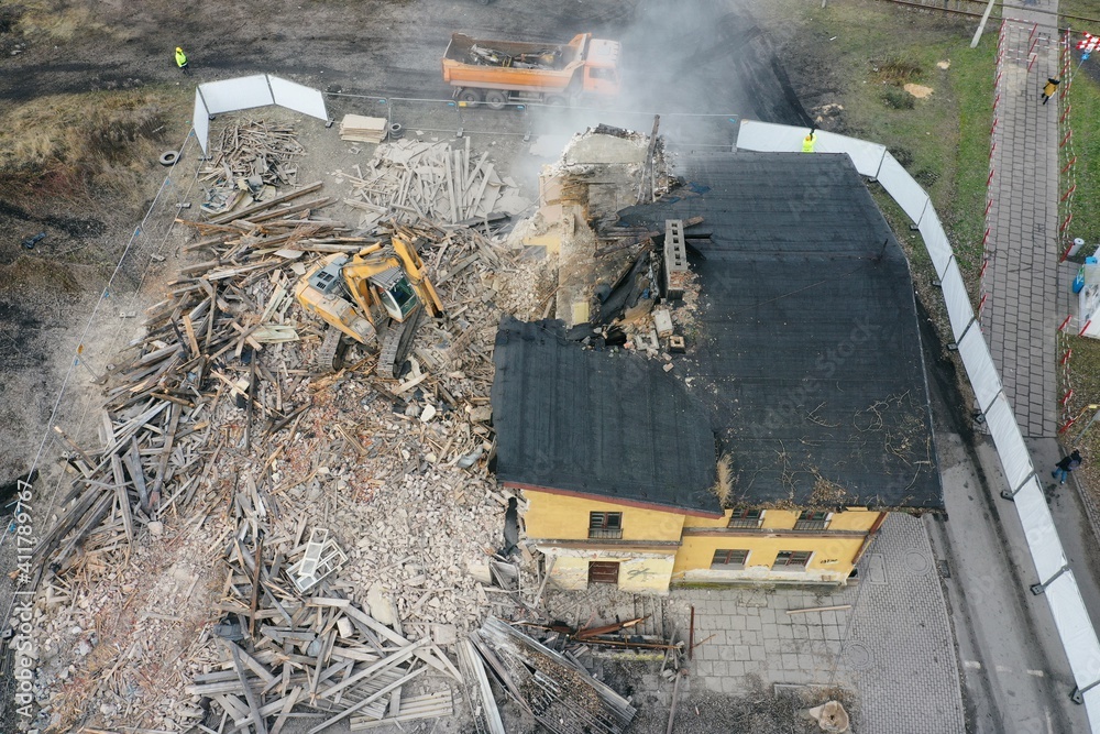 Yellow excavator destroys building. Heavy duty machine is demolishing a ...