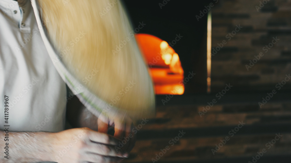 hands of pizza chefs throw pizza in the air, on the bottom of the oven ...