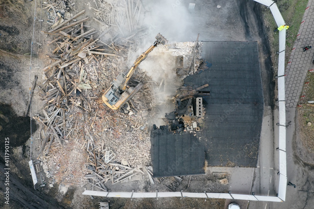 Yellow excavator destroys building. Heavy duty machine is demolishing a ...