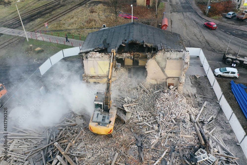 Yellow excavator destroys building. Heavy duty machine is demolishing a ...