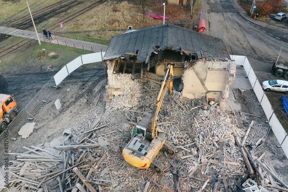 Yellow excavator destroys building. Heavy duty machine is demolishing a ...