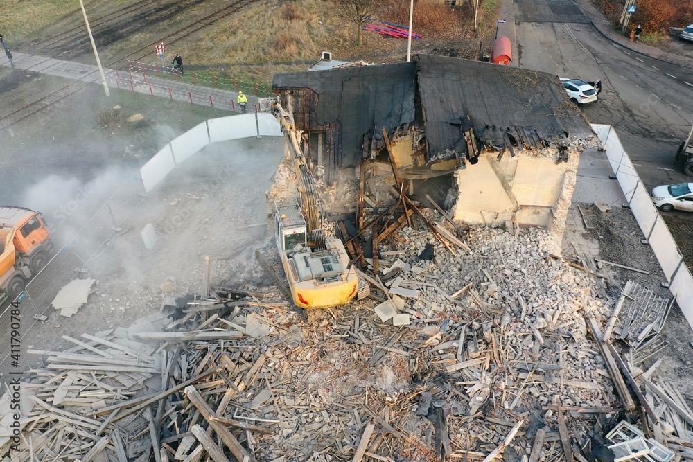 Yellow excavator destroys building. Heavy duty machine is demolishing a ...