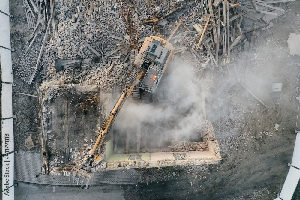 Yellow excavator destroys building. Heavy duty machine is demolishing a ...