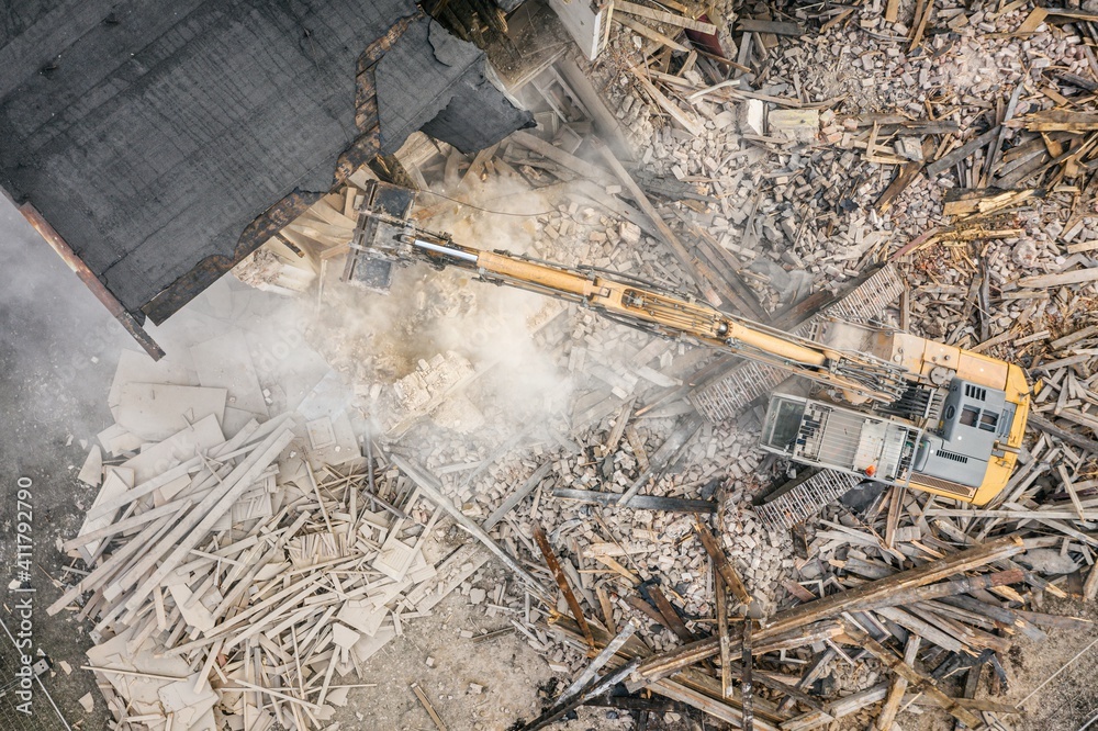 Yellow excavator destroys building. Heavy duty machine is demolishing a ...
