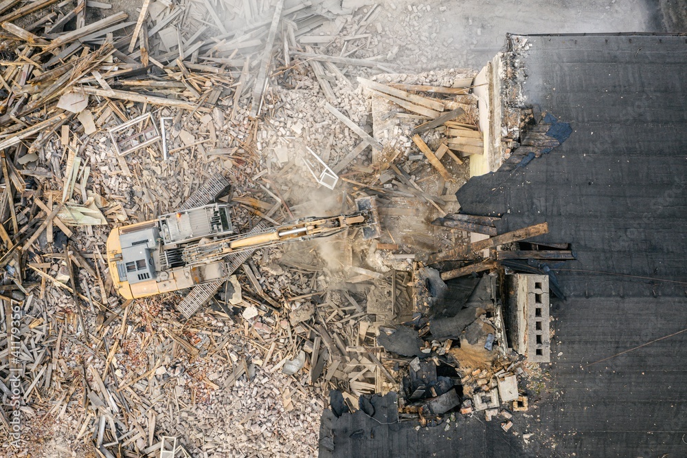 Yellow excavator destroys building. Heavy duty machine is demolishing a ...