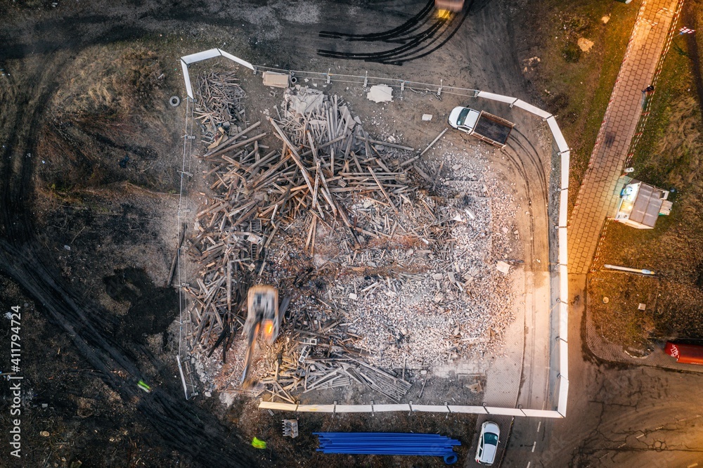 Yellow excavator destroys building. Heavy duty machine is demolishing a ...