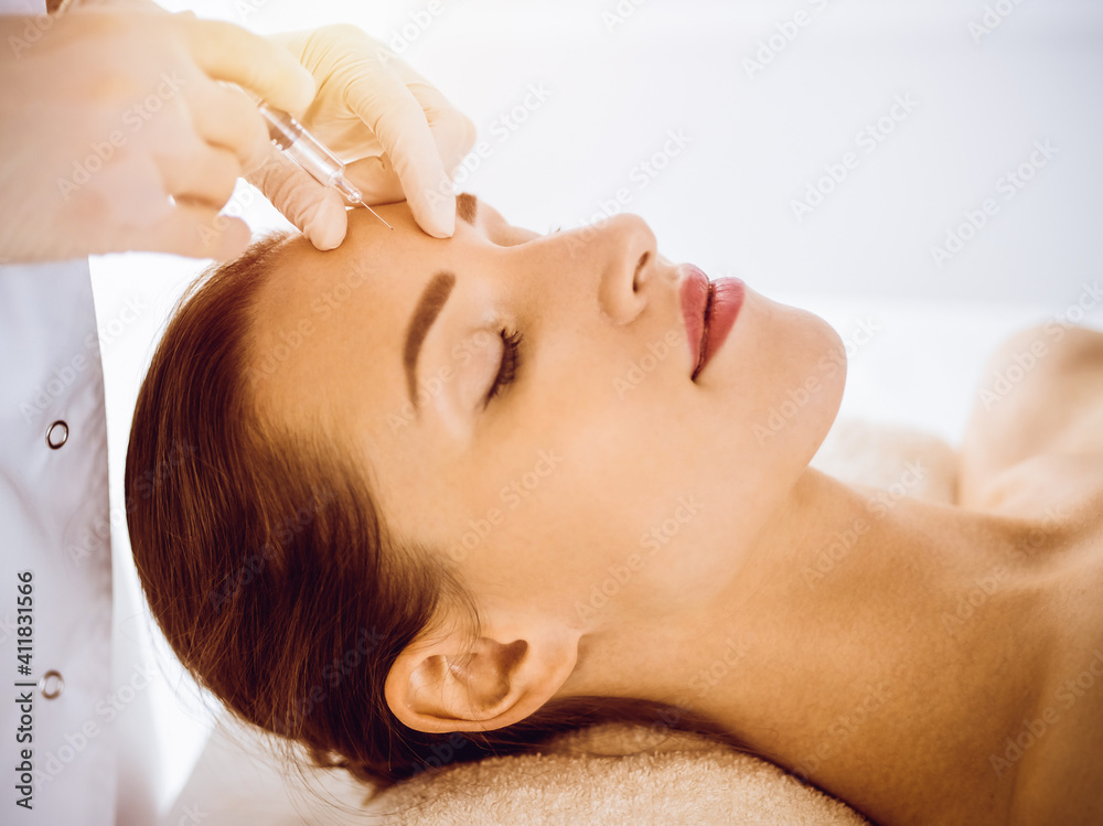 Beautiful woman receiving beauty injections with closed eyes in sunny ...