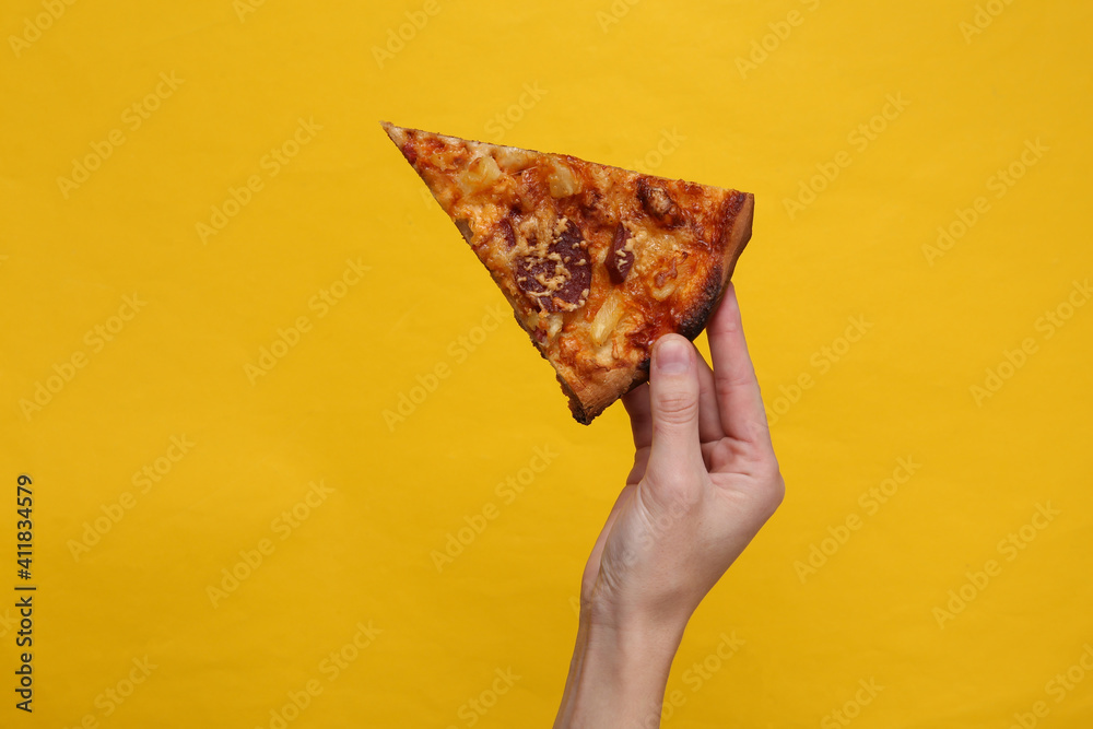 Hand holds piece of homemade pizza on a yellow background Stock Photo ...
