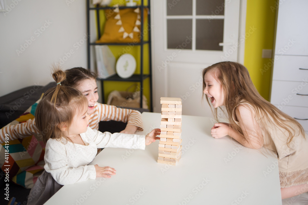 children play board game jenga. girls build tower of wooden blocks ...