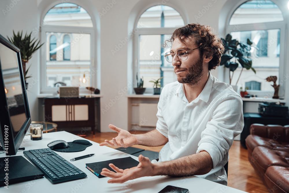 Portrait of a confused office worker which looks at computer screen and ...