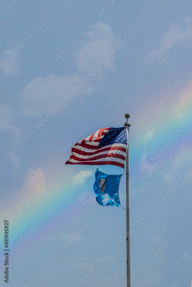 United States and Oklahoma flags flying high in front of rainbow sky ...