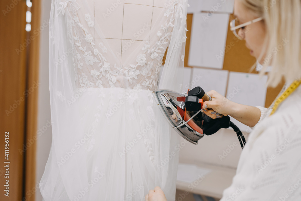 Woman ironing a lace wedding dress on mannequin using a steam iron ...
