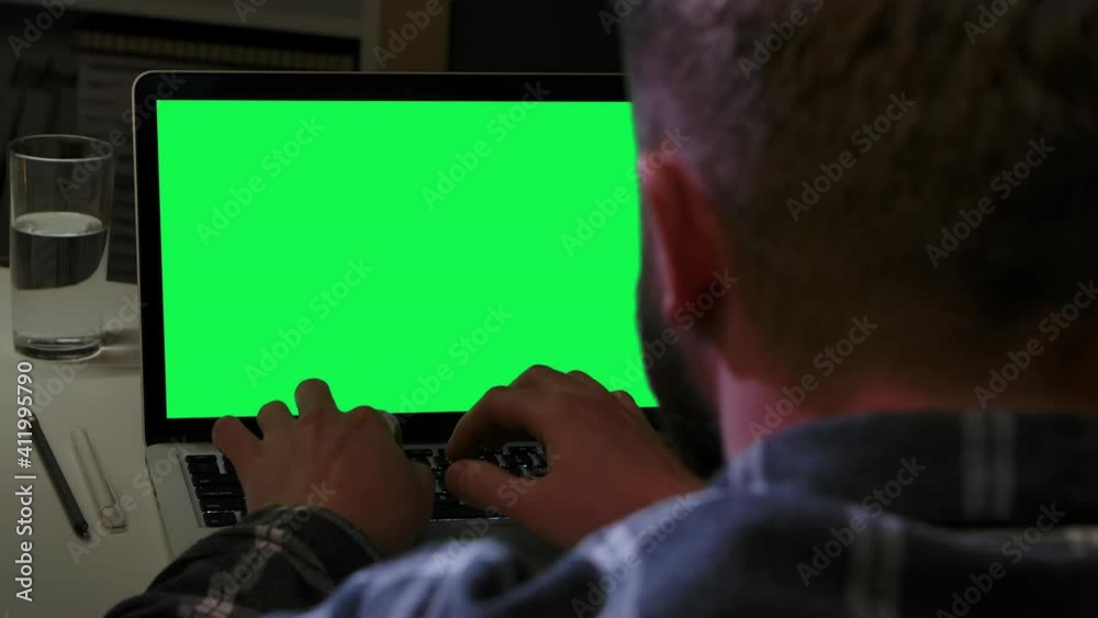 Man typing on laptop keyboard with green screen chroma key while ...