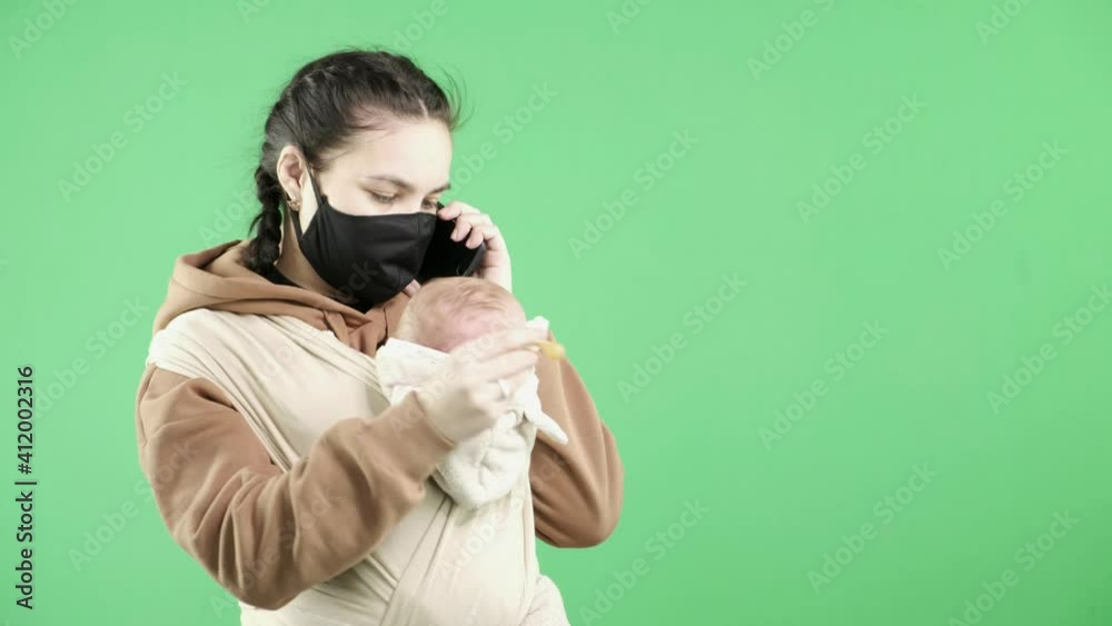 A tiny newborn baby in a baby sling, feeling protected from its ...