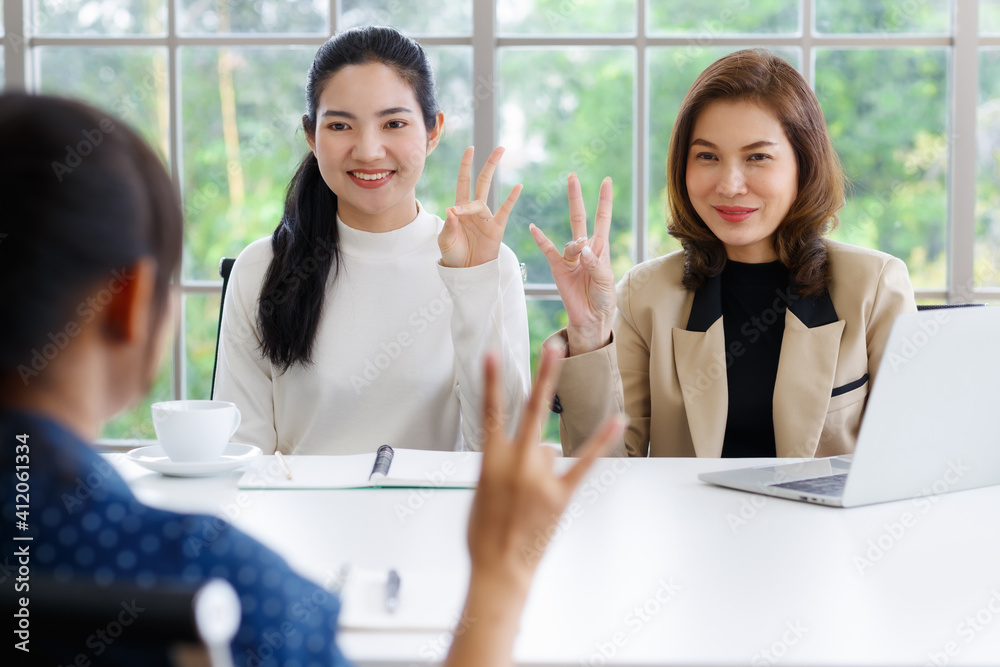 Deaf translator teaching two businesswomen to use and understand hand ...