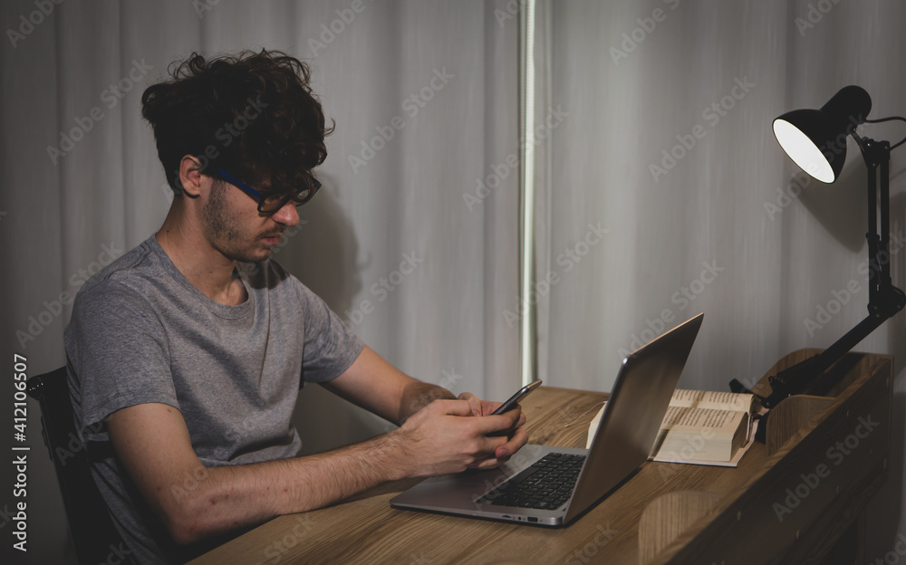 focused young caucasian man dressed casually sitting on a desk looking ...
