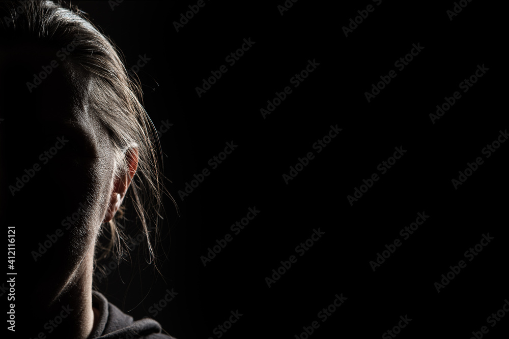 Half face of unrecognizable woman in shadow shrouded in darkness ...