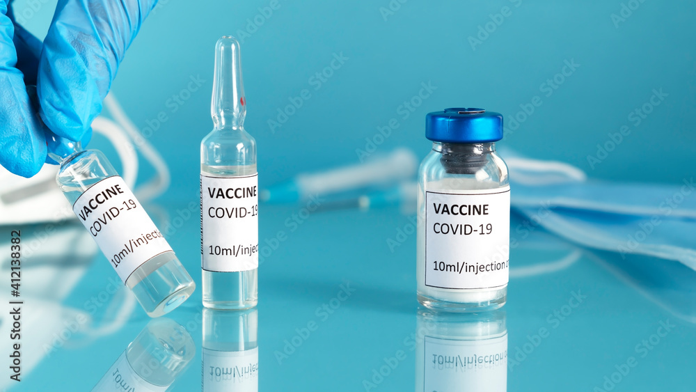 The doctor's hand in a blue medical glove takes a vaccine vial for ...
