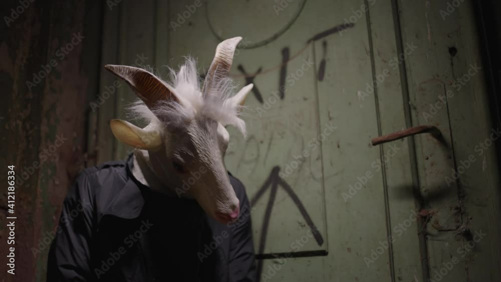 Close up of a masked person shaking in a ruined house. Possessed maniac ...