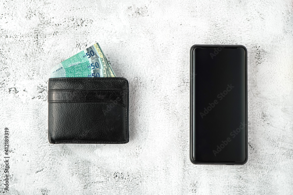 Ringgit Malaysia notes in the black wallet and black mobile smartphone ...