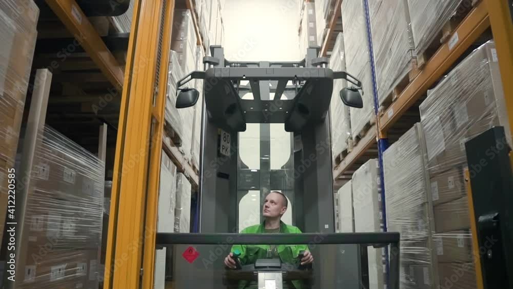 Warehouse male worker at forklift. loader unload goods from shelf ...