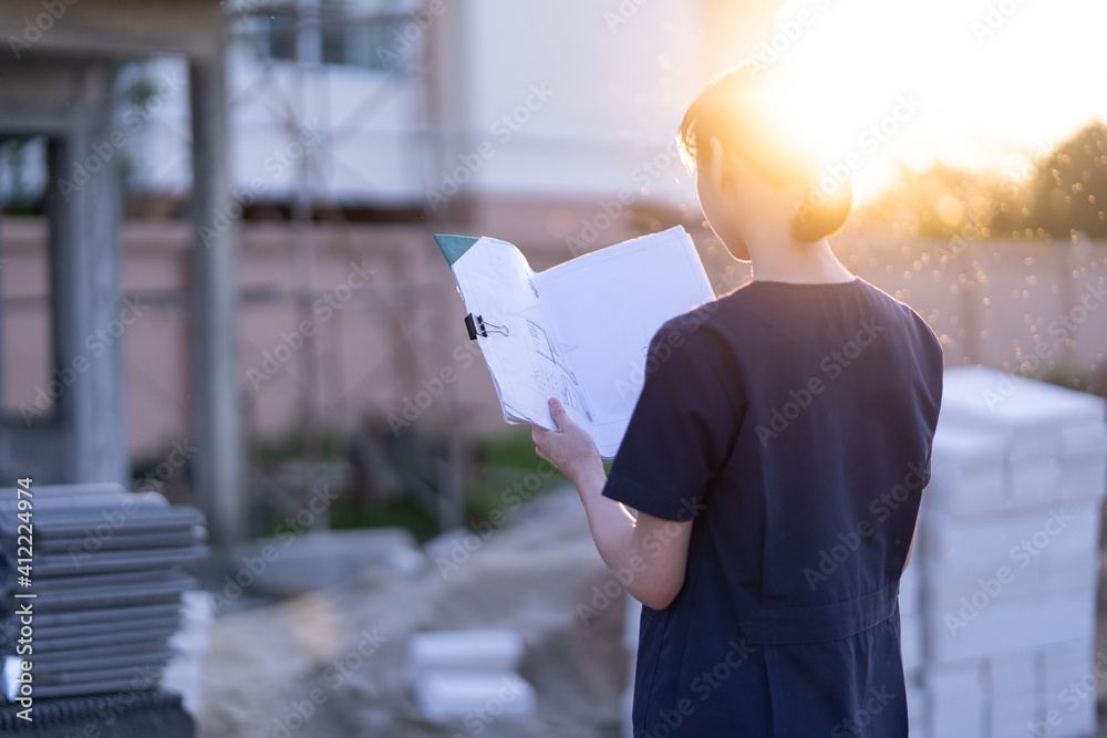 Young Asian architect look at blueprint and plan to building homes on ...