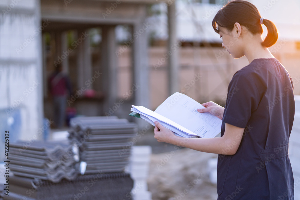 Young Asian architect look at blueprint and plan to building homes on ...