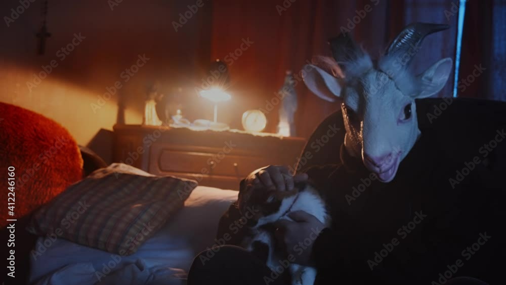 Eerie scene of a scary, masked stranger sitting in a dark living room ...