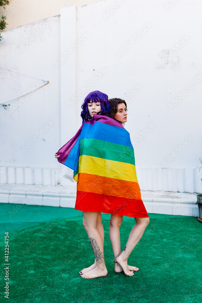 Two women with rainbow flag on a backyard. Couple Young lesbian girls ...