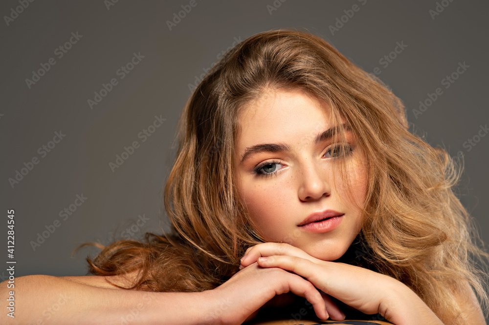 Pretty young woman with long brown hair looking at camera. Closeup ...