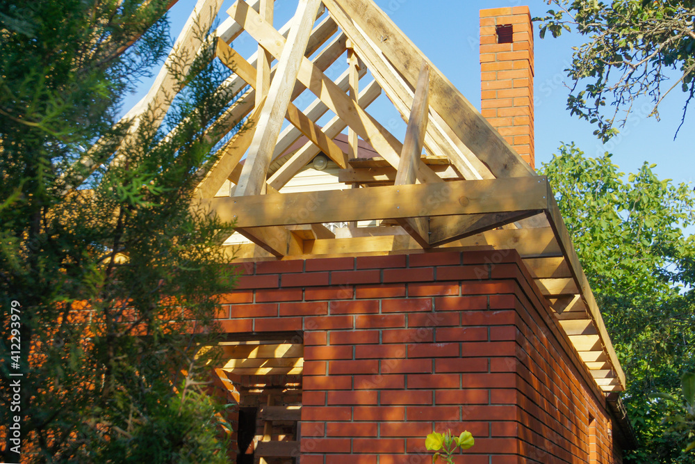 Rafter system of gable roof of one-story country cottage against blue ...