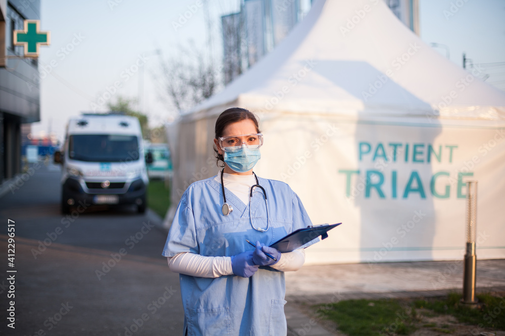 Portrait of serious female key front line worker in blue PPE uniform ...