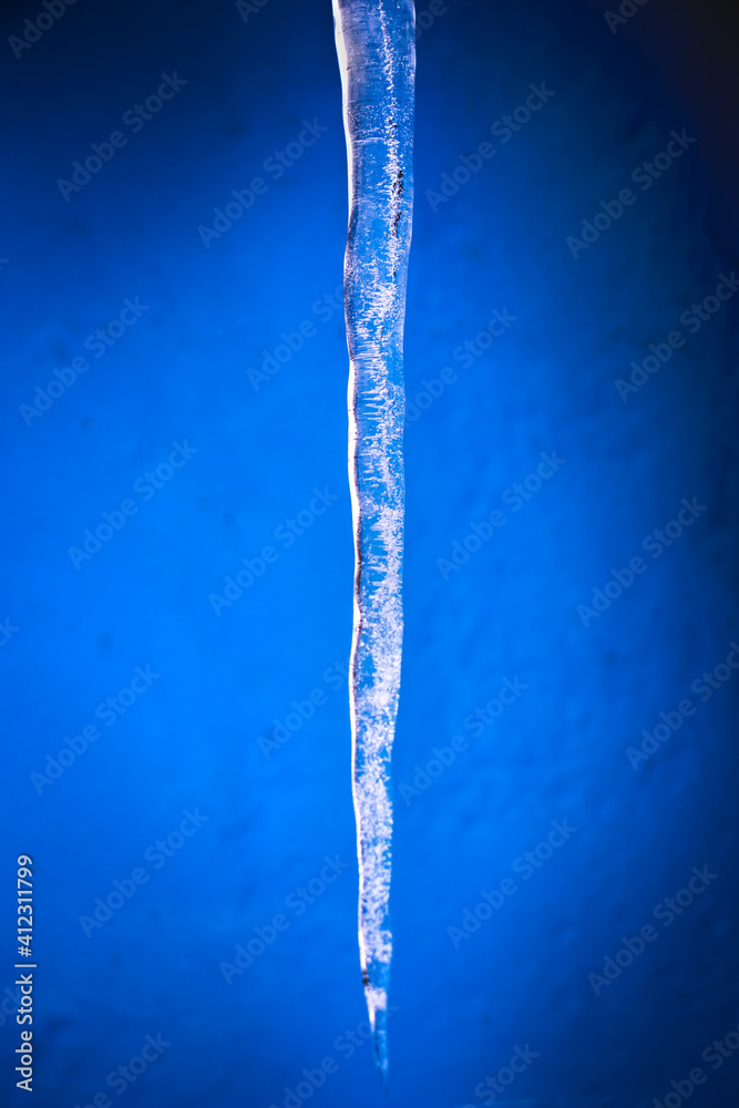 Shot of an icicle isolated on a blue background. The colors are highly ...