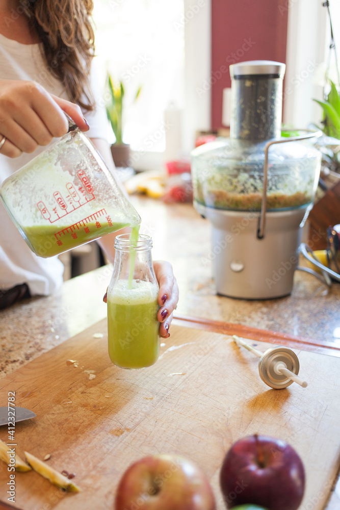 Woman pouring a fresh green juice in a jar in her bright kitchen. Stock ...