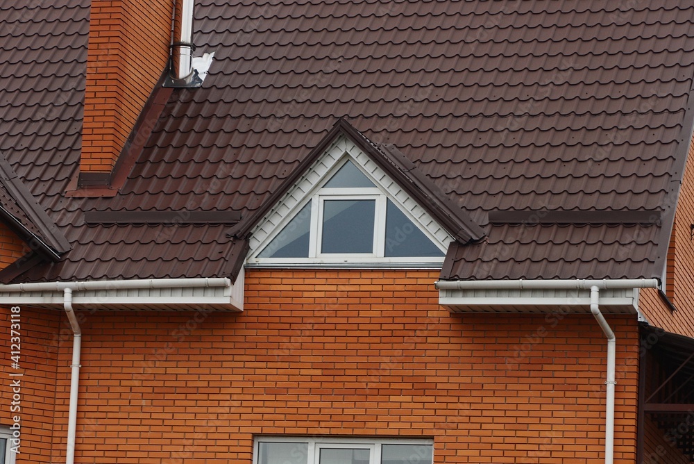 one white triangular window on a red brick wall of the attic of a ...