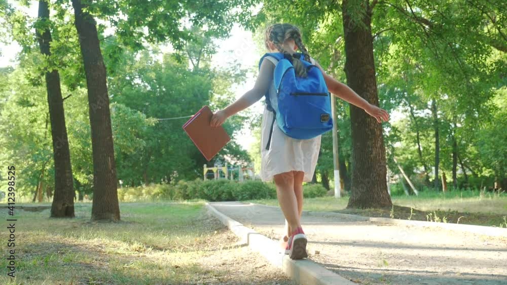 schoolgirl goes to school through the park along the path. kid dream ...