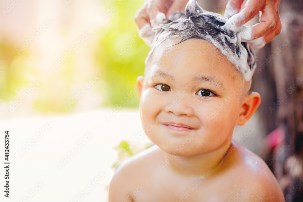 Mom using shampoo to washes her son in the outdoor shower. Parents care ...