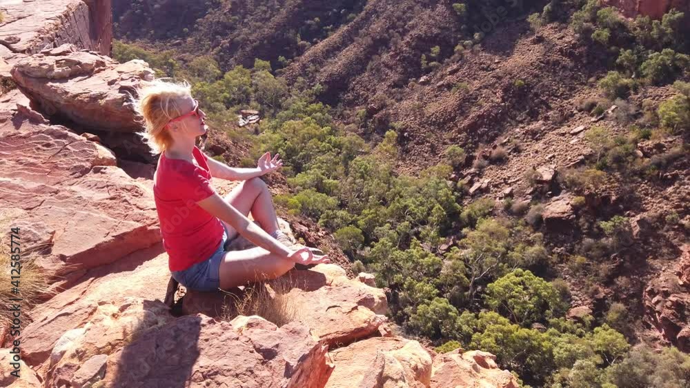 woman doing yoga meditation in lotus pose at edge of Kings Canyon in ...