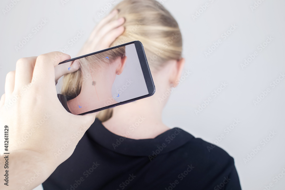 The woman shows his neck with a chip implanted which is read or scanned ...