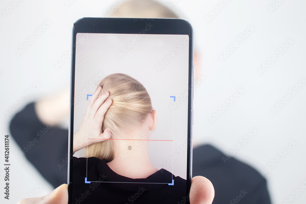 The woman shows his neck with a chip implanted which is read or scanned ...