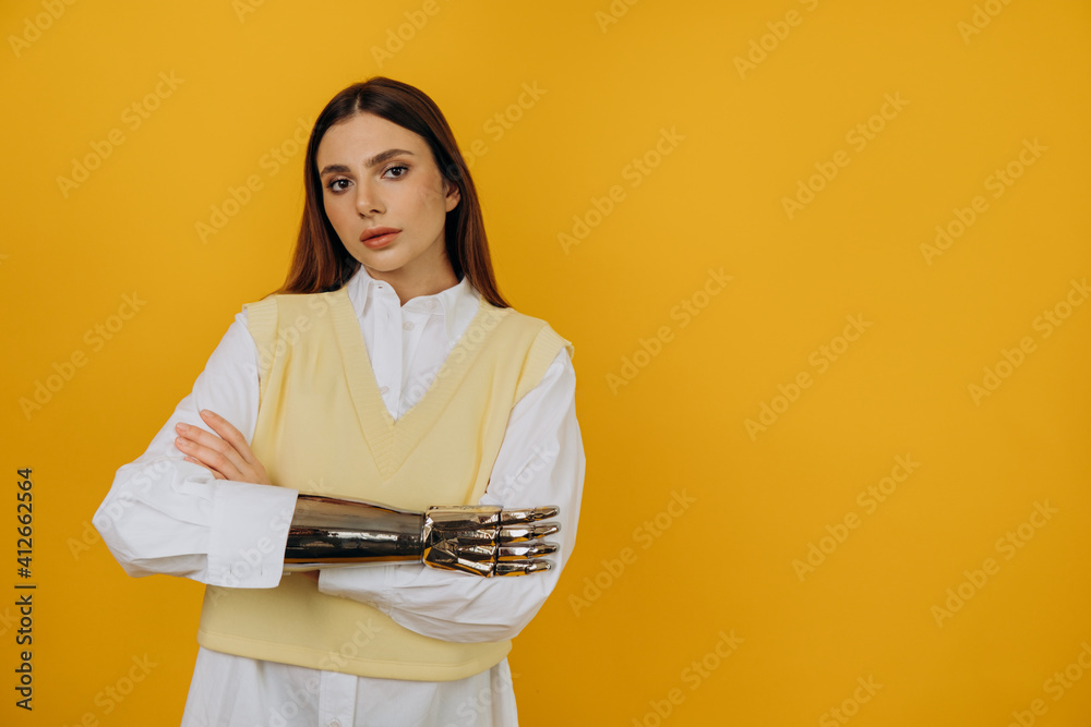 Portrait of a beautiful young woman with a silver bionic prosthetic arm ...