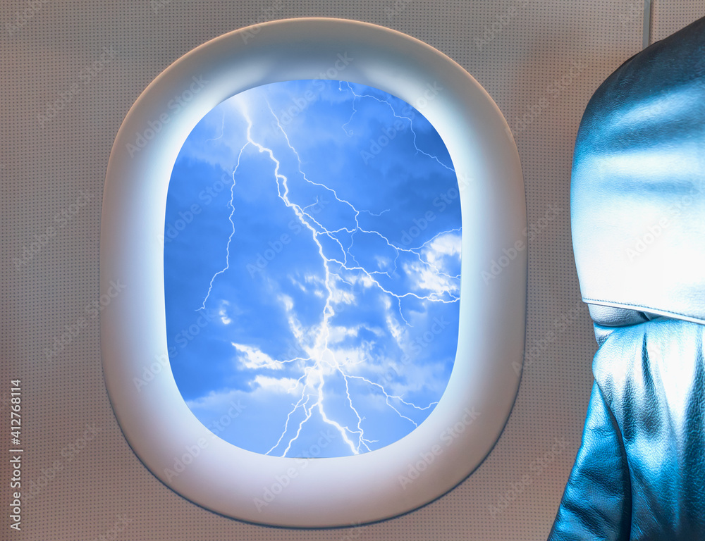 Airplane in the sky with thunder and lightning as seen through window ...
