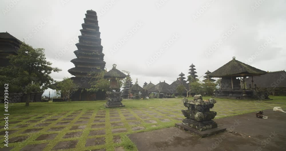 Tilting dolly shot of grassy temple grounds with black stone statues ...