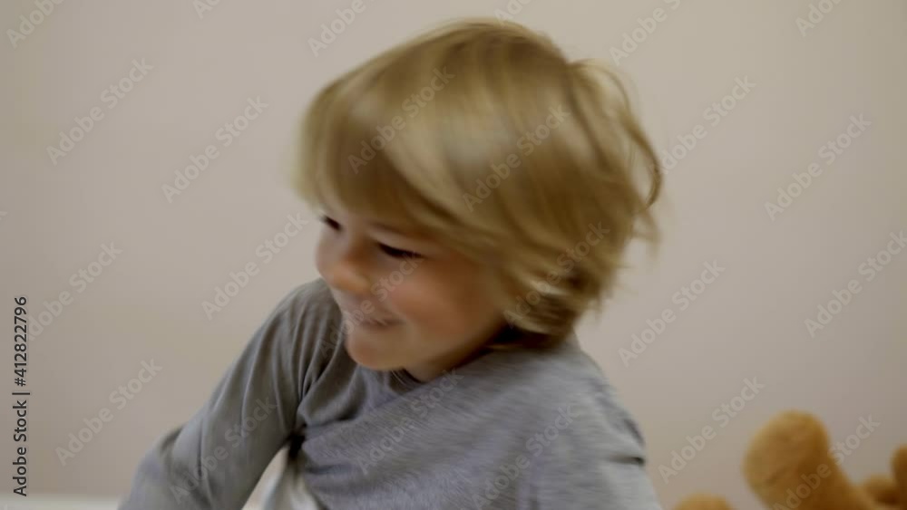 Side view of happy cute boy waking up in bedroom. Joyful smiling ...